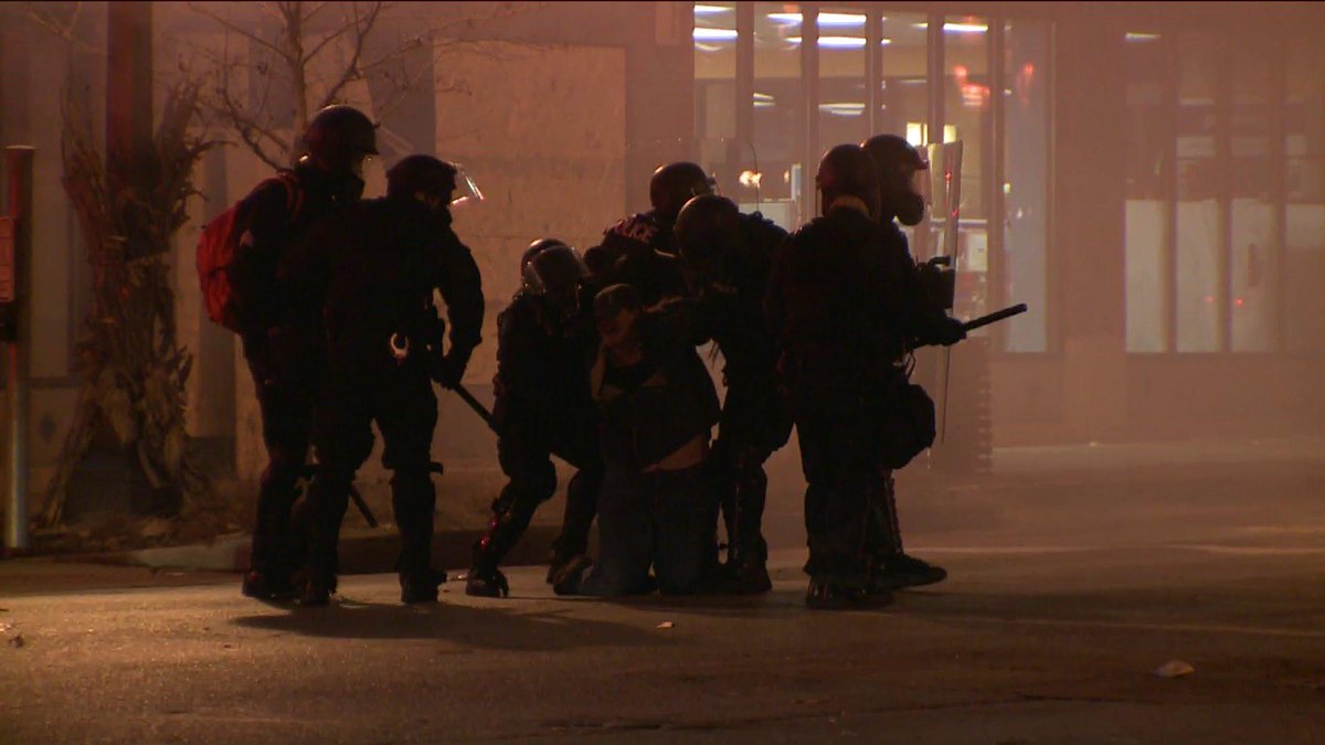Police helping a man in tear gas off the ground during the riots ...