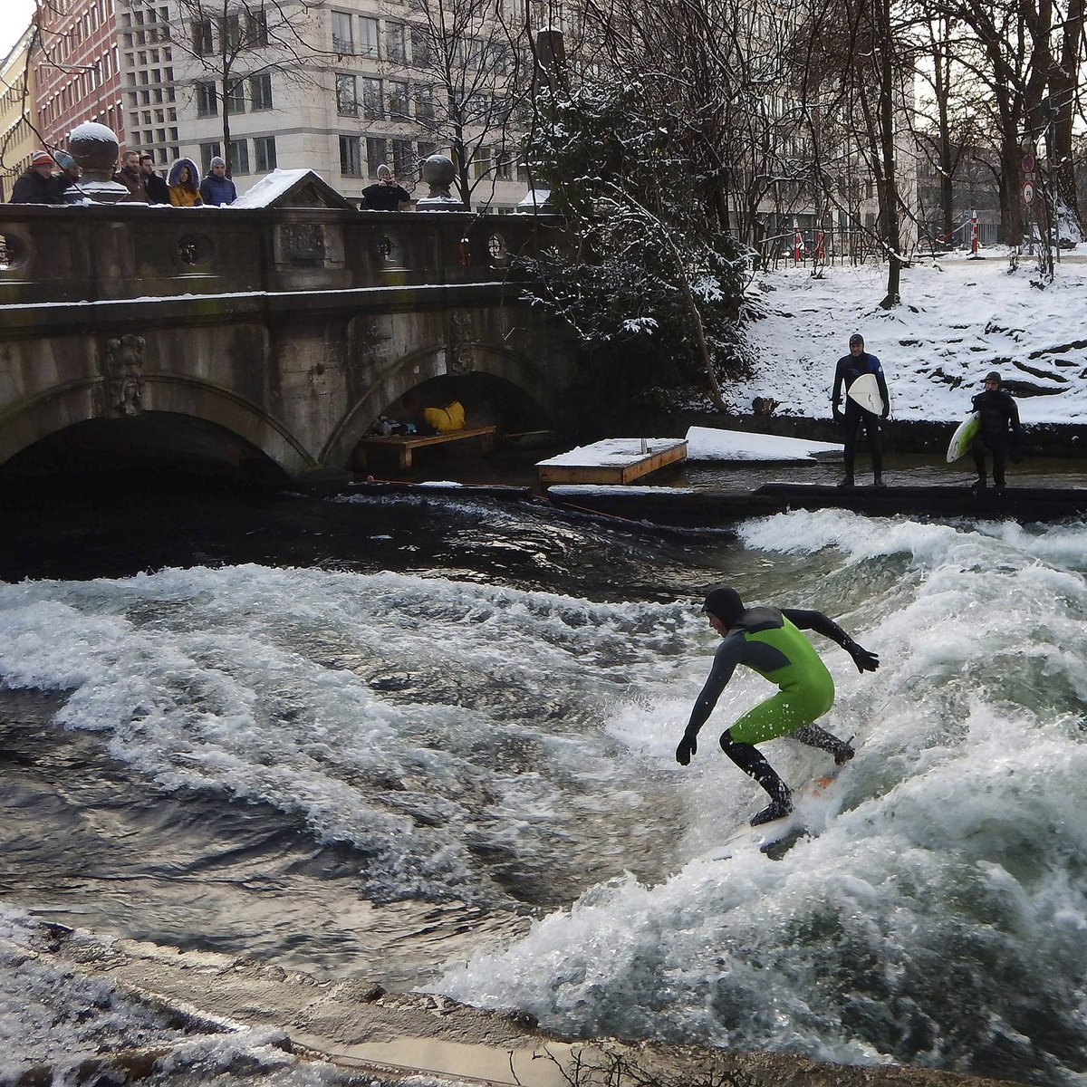 Surfers ride the eisbach canal wave at the isar river in the english ...