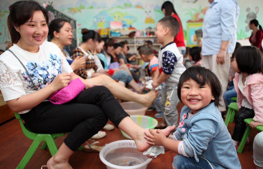 Day: Children help wash their mothers' feet during an activity to celebr...