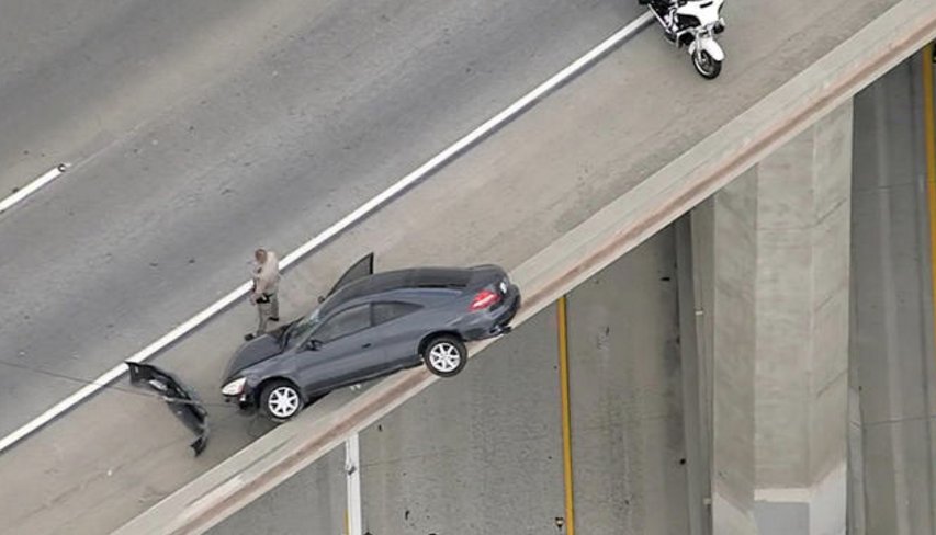 A car is teetering on the edge of a freeway connector overpass in ...