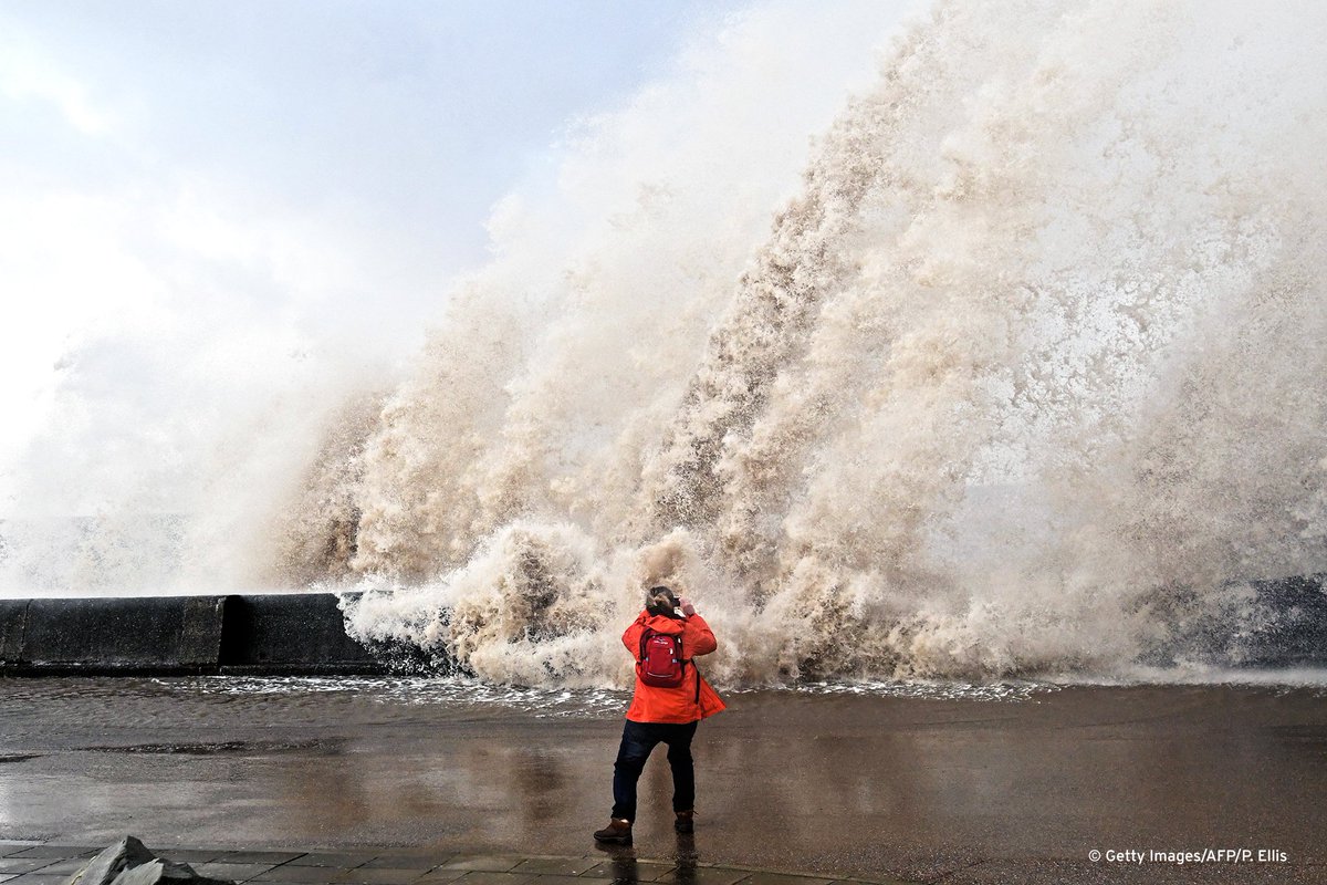 Our pic of the day: A woman takes photographs as waves crash over the ...