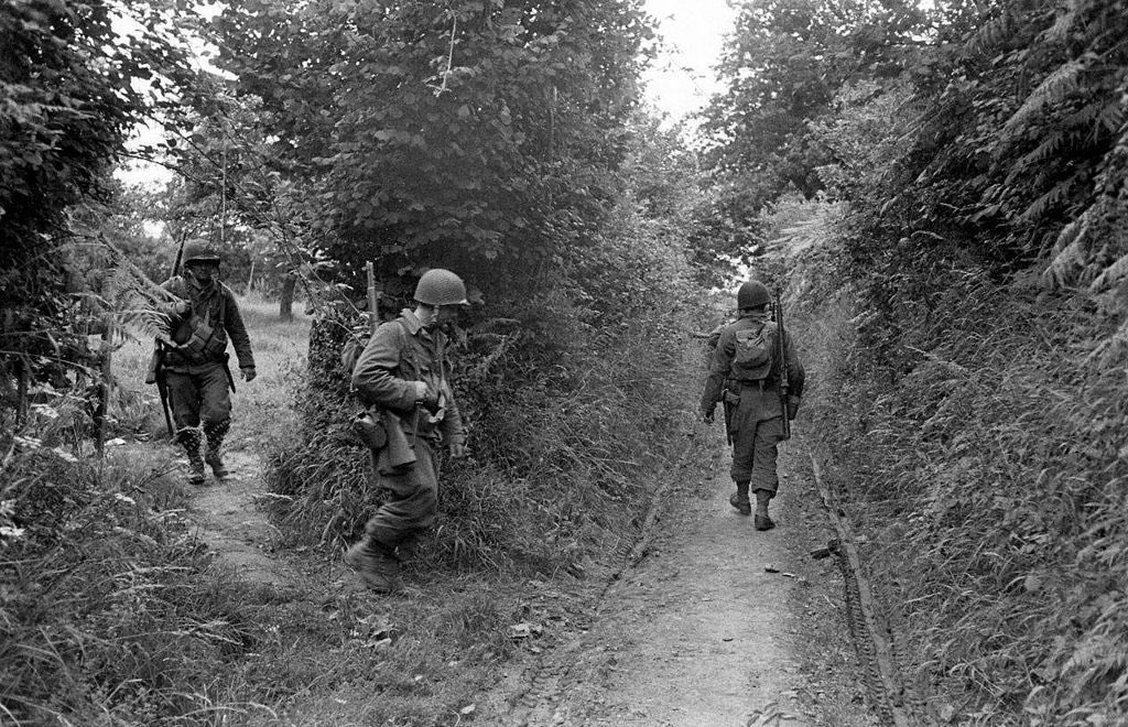 Infantrymen passing hedgerow landscape Normandy | World War II History ...