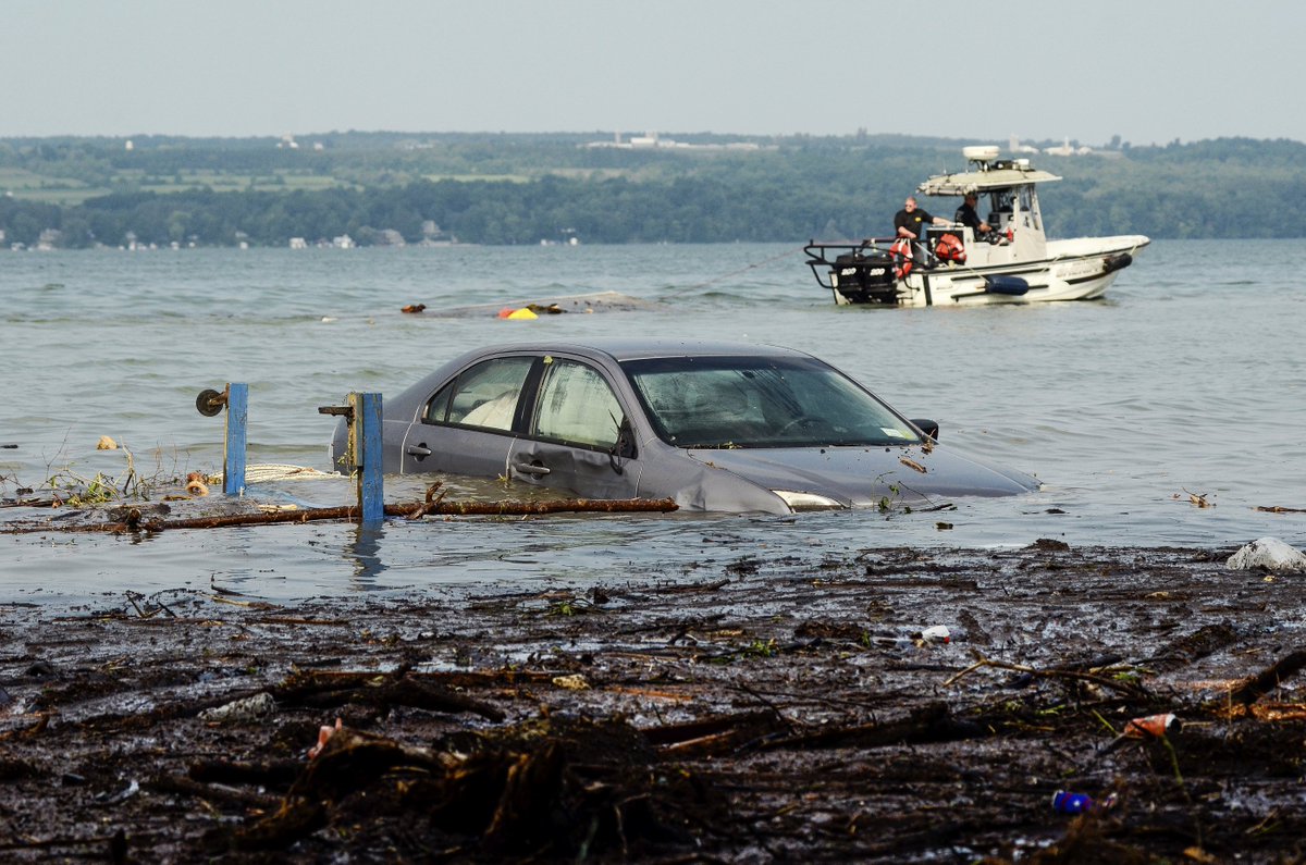 A car floats in Seneca Lake as crews attempt to drag a shed out of the ...