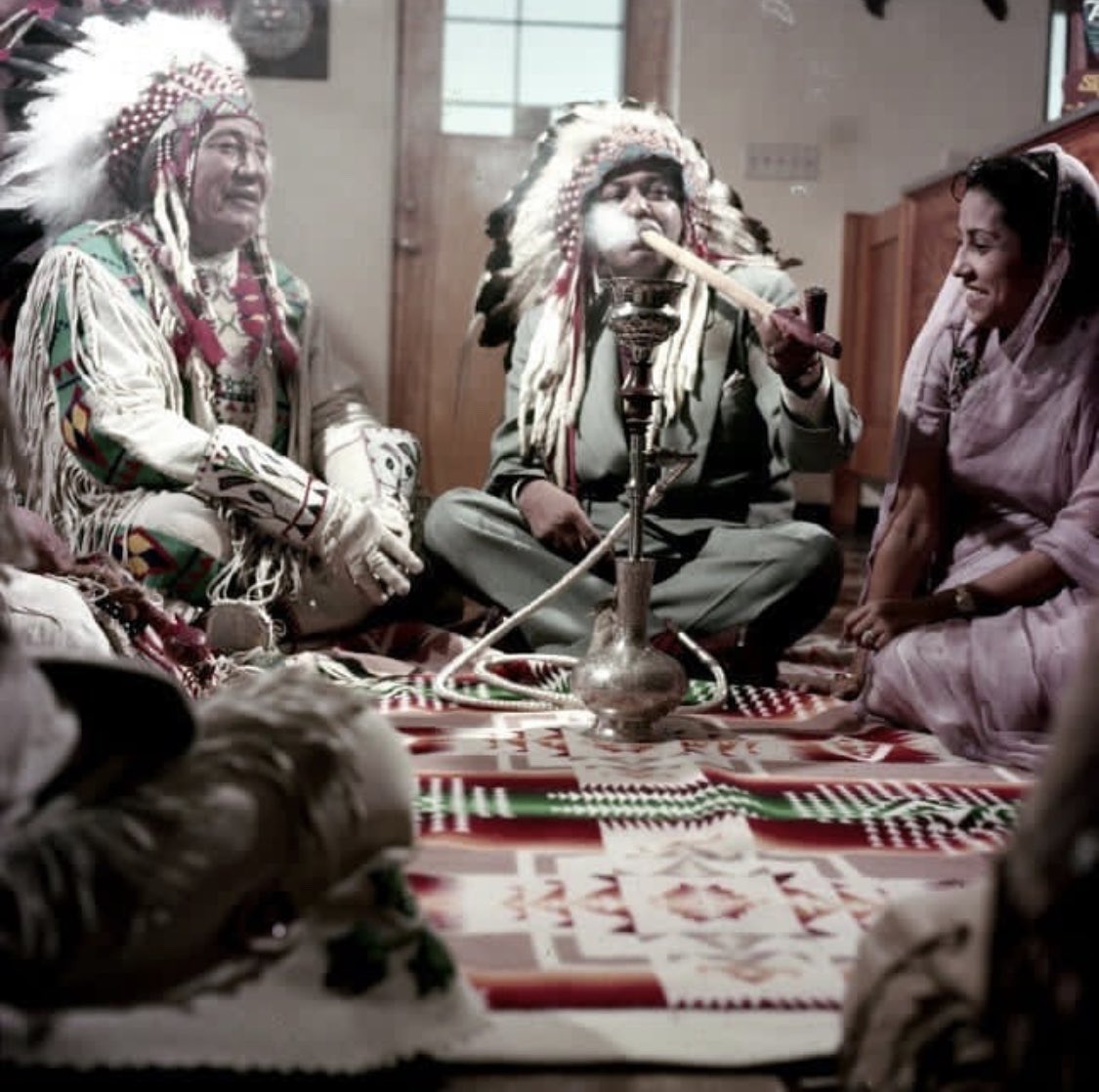 1954. Pakistan PM Mohd Ali Bogra and his wife smoke the peace pipe with ...