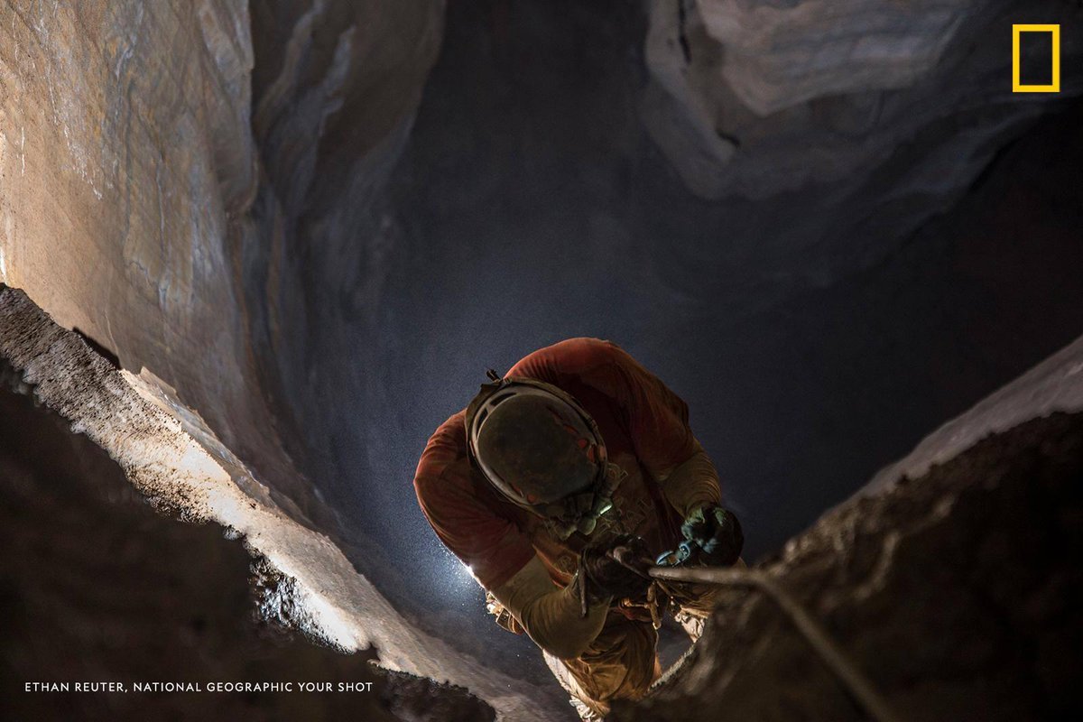 A caver descends into the inky darkness of a vertical chasm in this ...