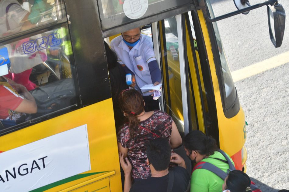 Commuters board a bus along Commonwealth Avenue in Quezon City, amid ...
