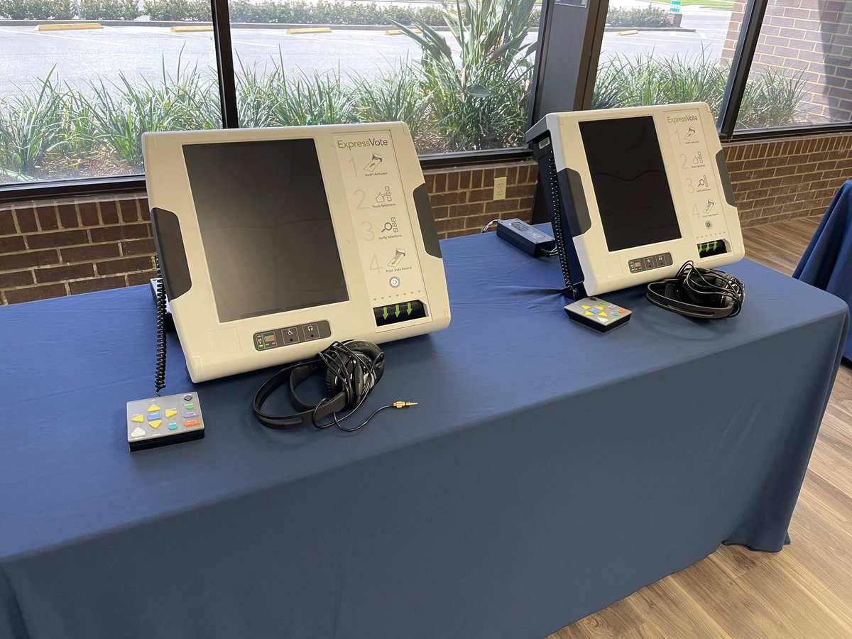 2 ExpressVote machines on a table with blue tablecloth, with headphones ...