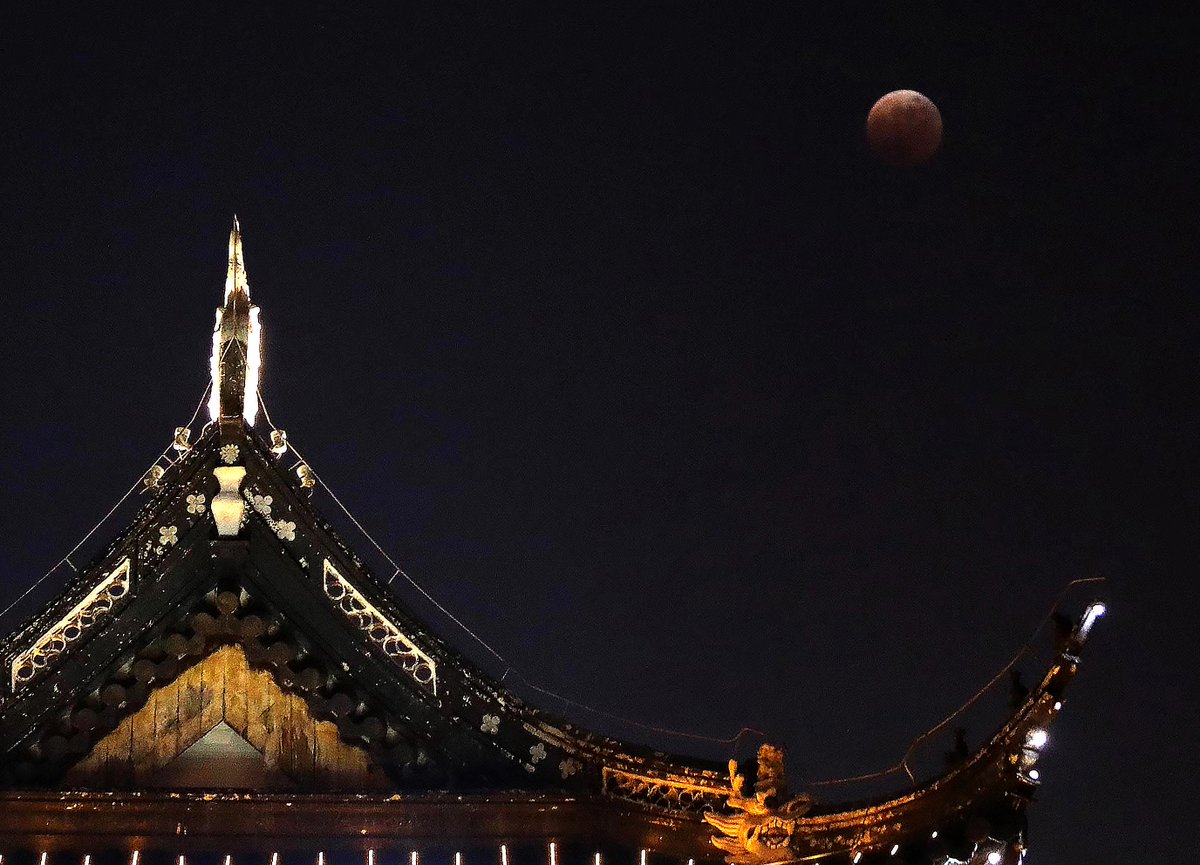 A total lunar eclipse is observed above the tower of the ancient ...
