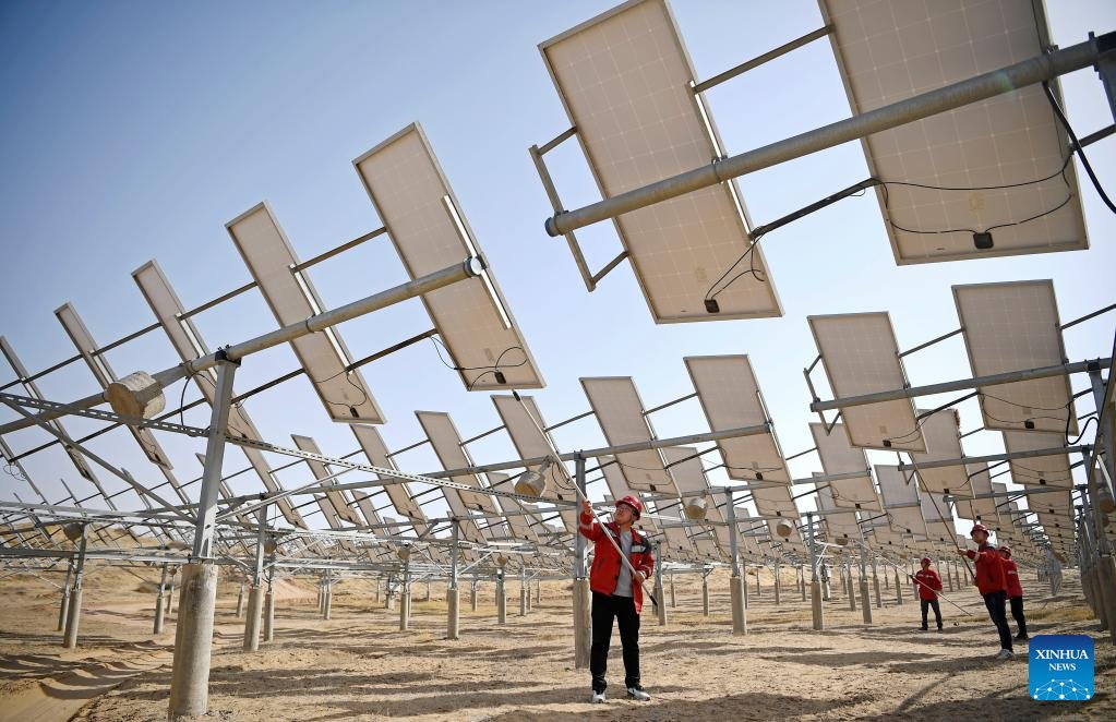 Workers dust photovoltaic panels after windy weather at a photovoltaic ...